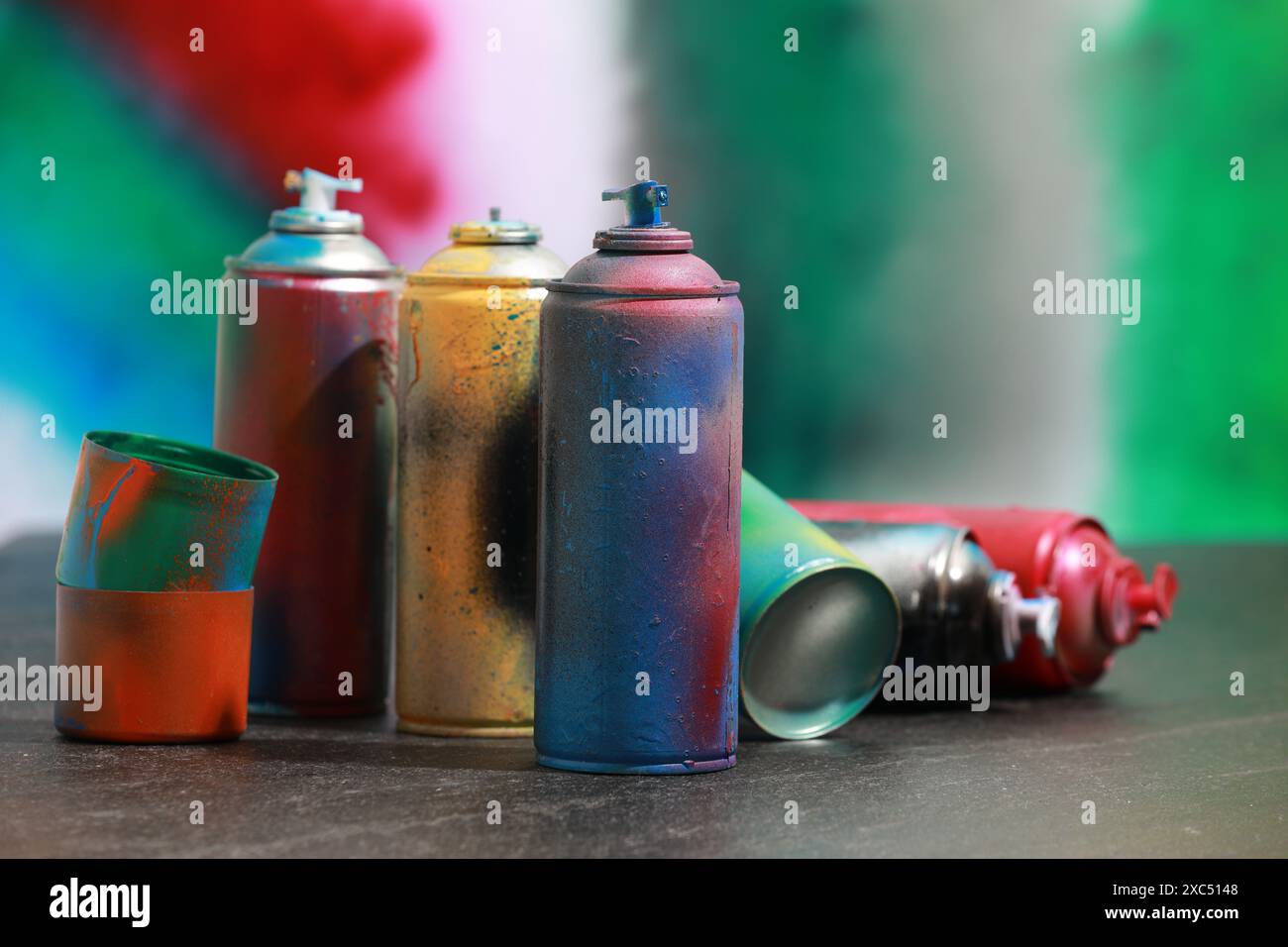 Many spray paint cans on gray surface against color background Stock ...