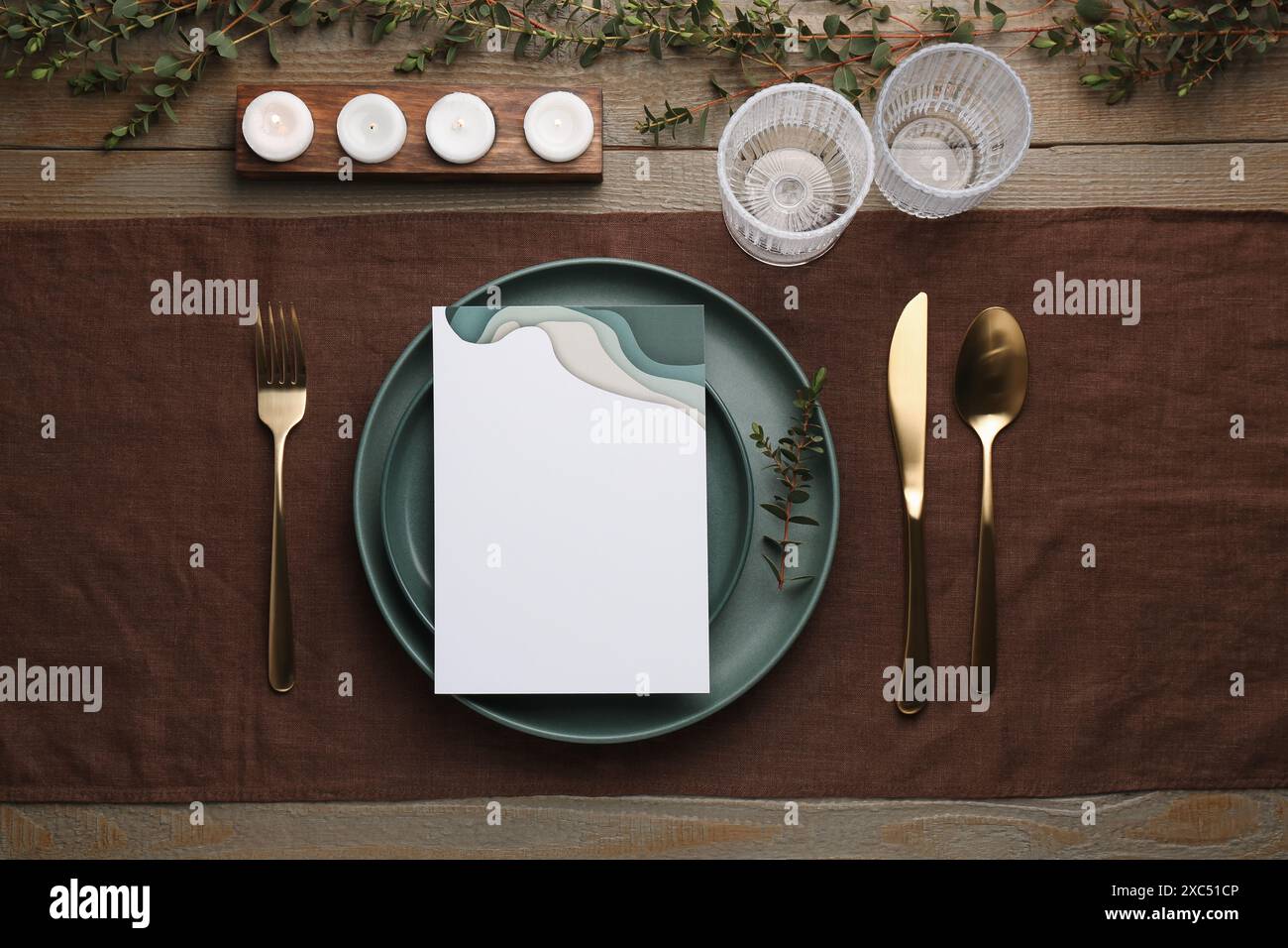 Empty menu, plates, cutlery, glasses and decor on wooden table, top ...