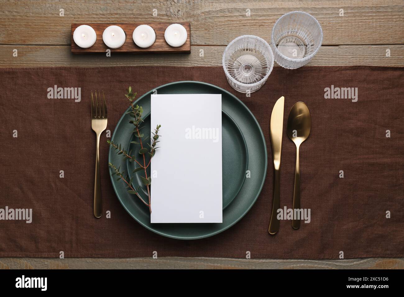 Empty menu, plates, cutlery, glasses and decor on wooden table, top ...