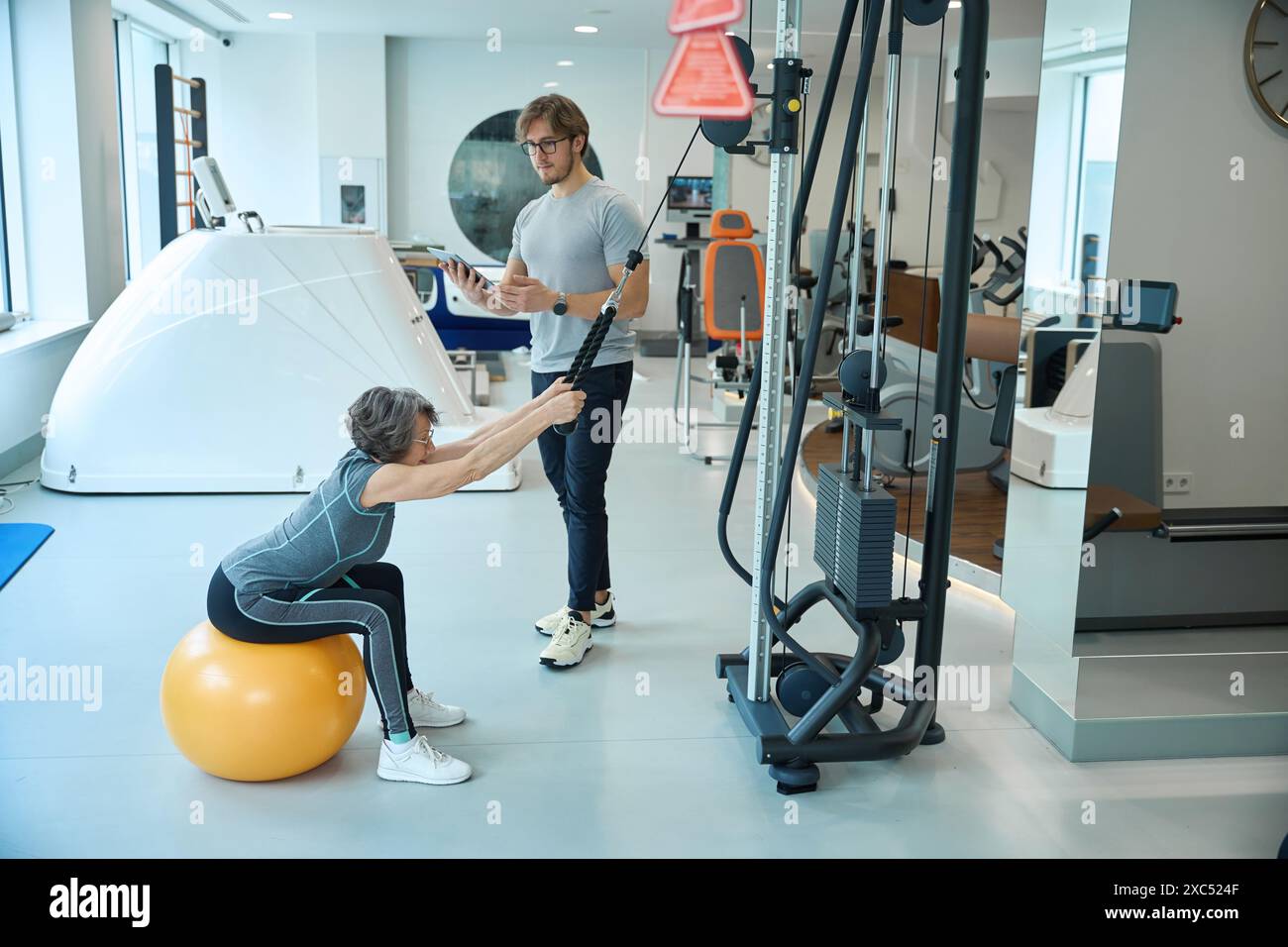 Fitness clinic patient works out in gym under supervision of ...