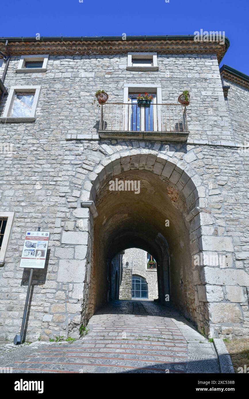 A historic stone archway leading to a quaint street in a European town ...