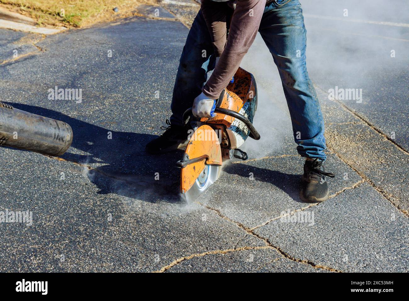 Using diamond blade saw machine, construction worker cuts asphalt ...