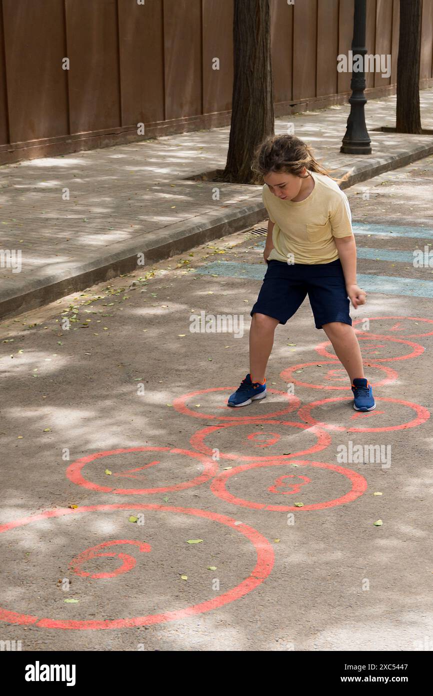 A happy boy plays hopscotch on the street at the beginning of the ...