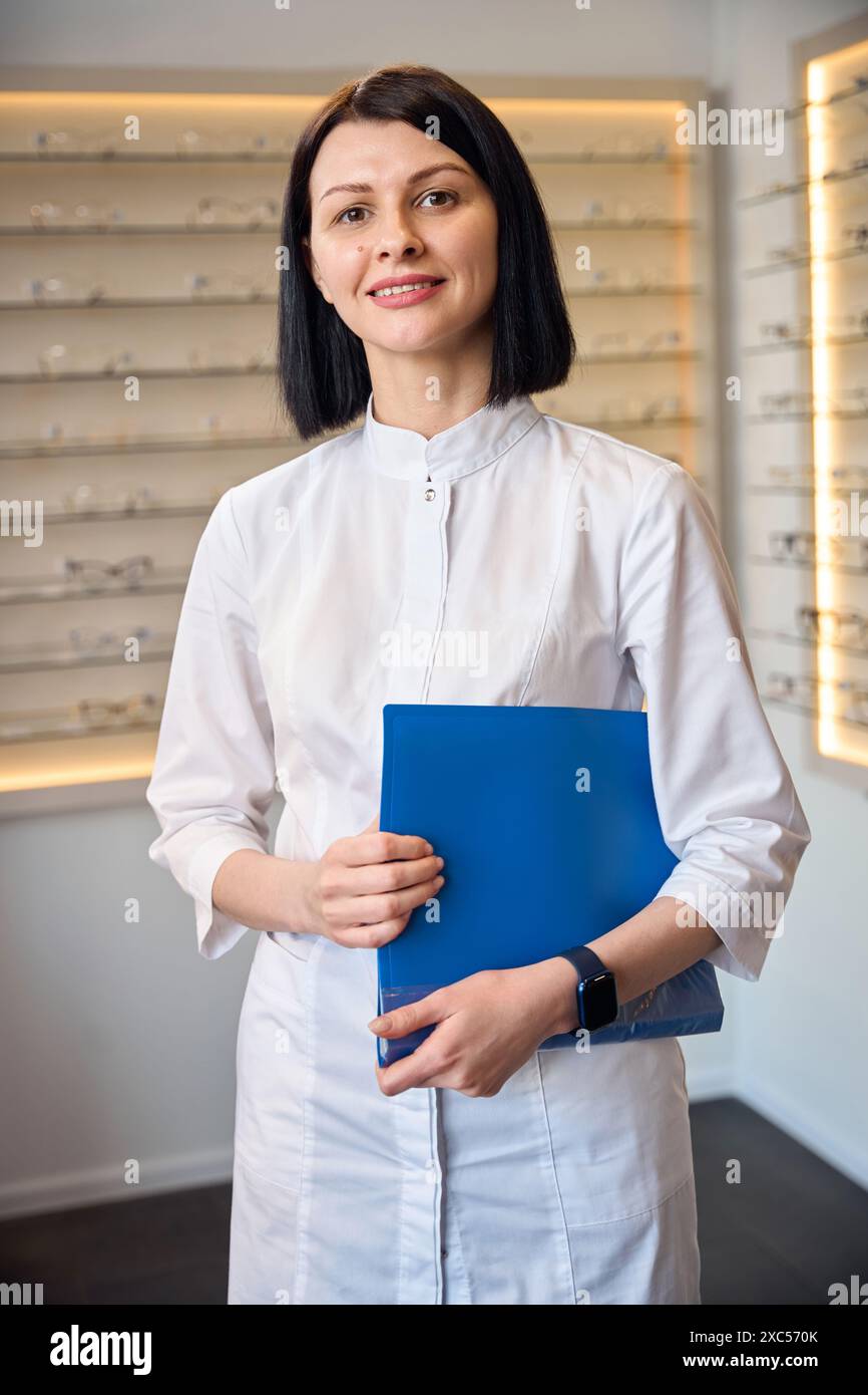 Optical employee stands at a display case with glasses Stock Photo - Alamy