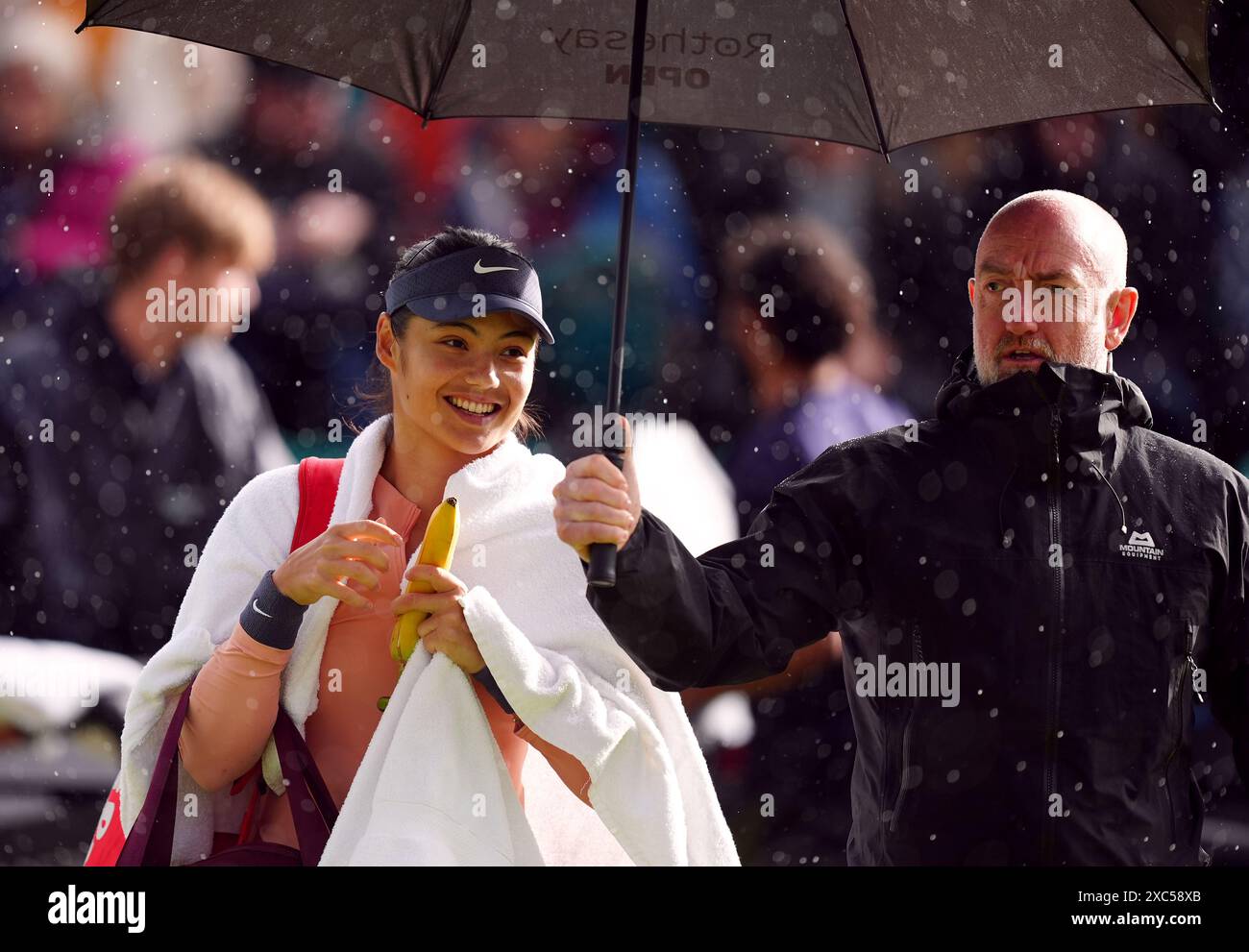 Emma Raducanu shelters under an umbrella as rain suspends her match ...