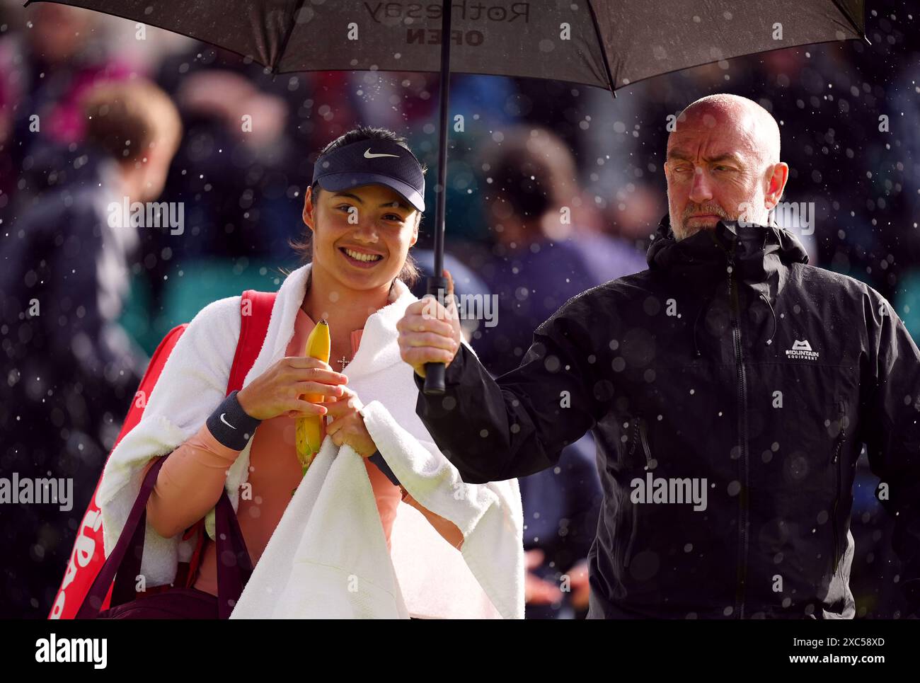 Emma Raducanu shelters under an umbrella as rain suspends her match ...