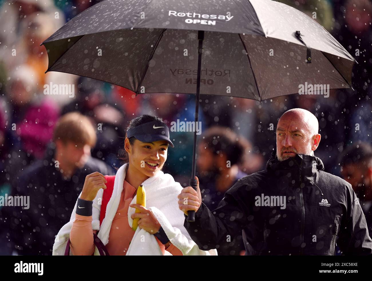 Emma Raducanu shelters under an umbrella as rain suspends her match ...