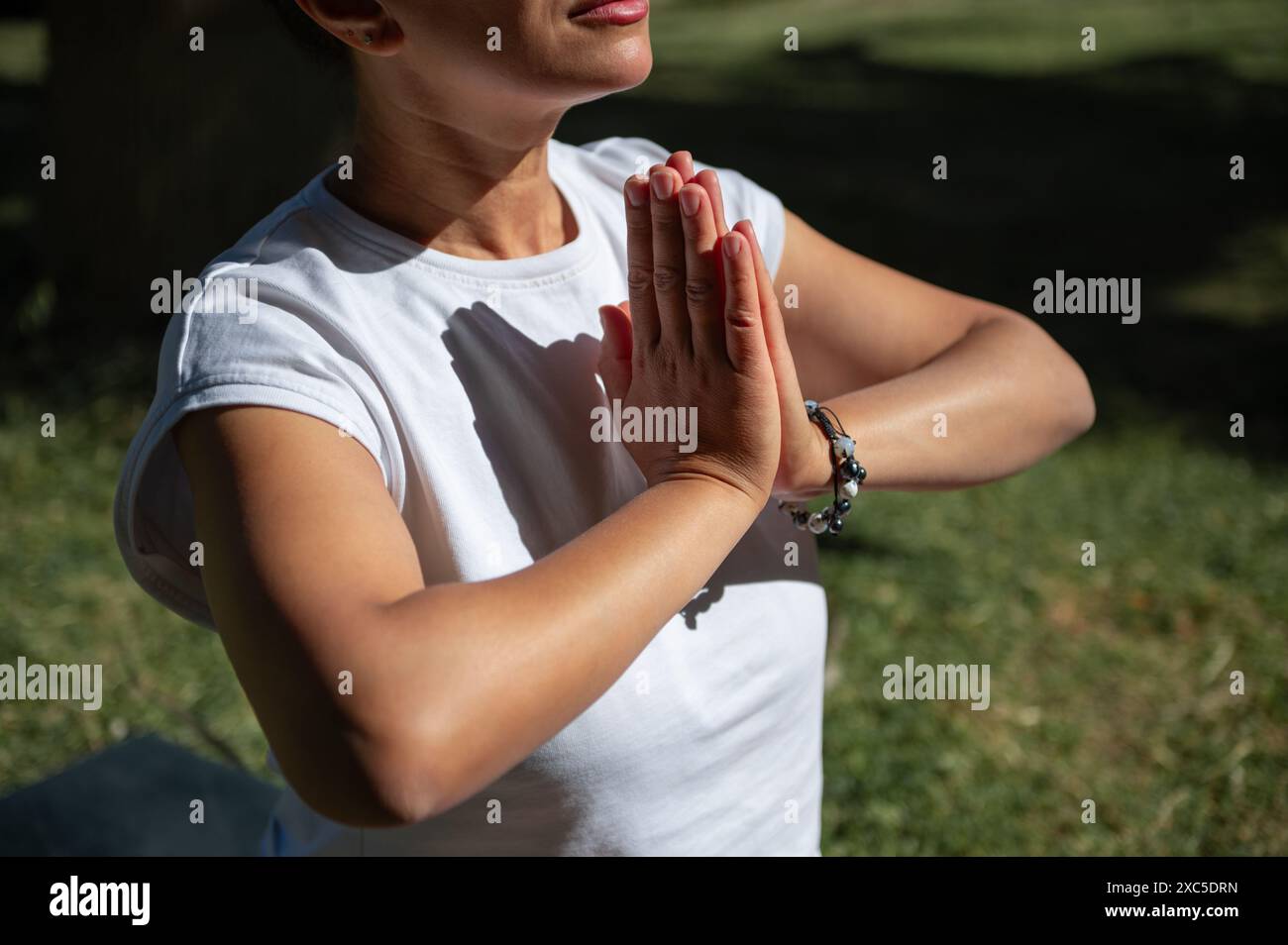Close-up of a woman practicing yoga outdoors with hands in prayer ...