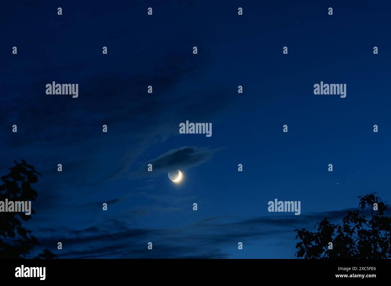 The growing moon on the background of the blue sky at night. Astrophoto ...