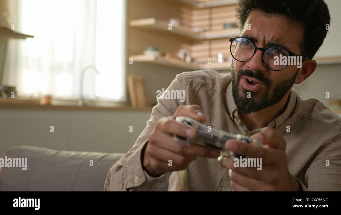 Addicted male gamer Arabian Indian man guy on couch play video game ...