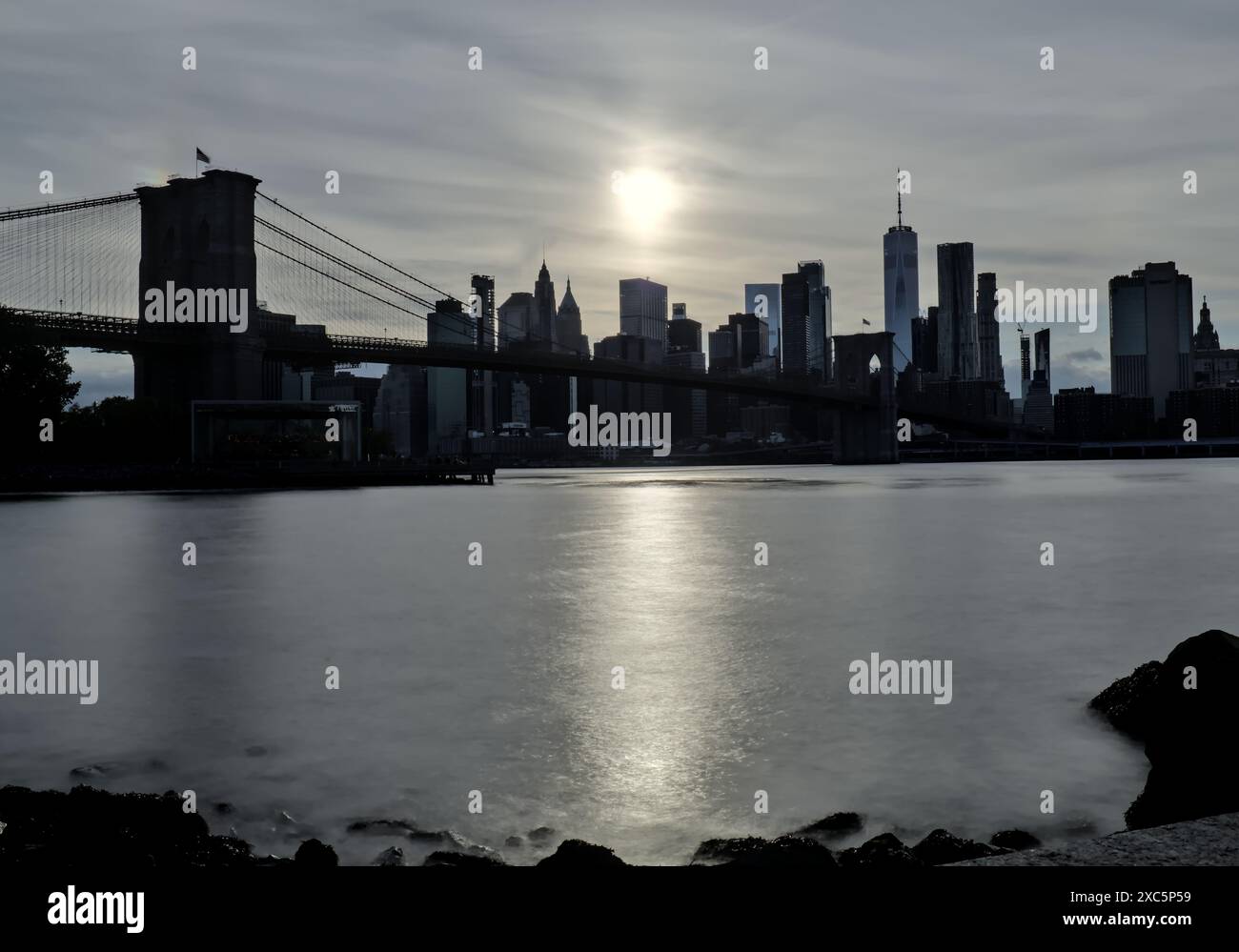 sun setting behind silhouette of new york city downtown skyline with ...
