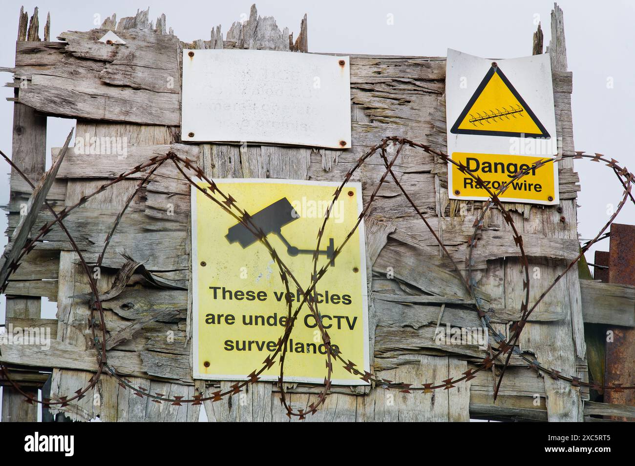 Razor wire warning sign on security fence at construction site Stock ...