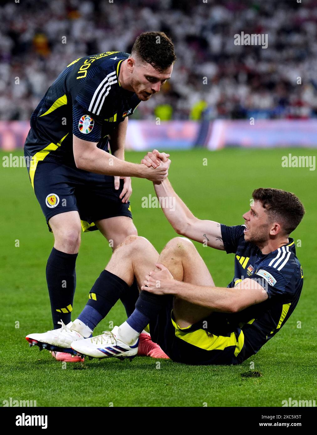 Scotland's Ryan Christie is helped to his feet by team-mate Andrew ...