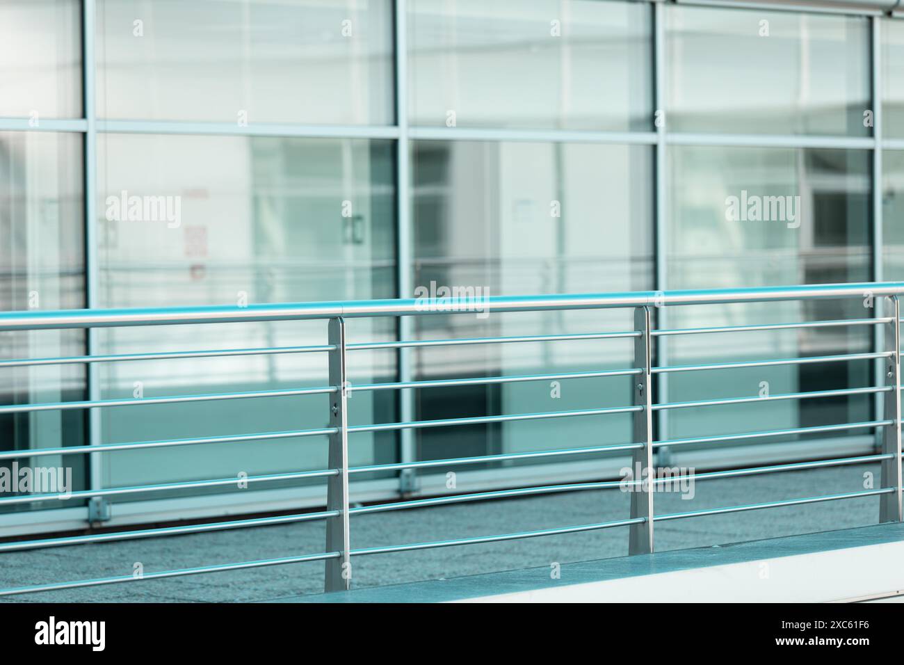 modern, metal railing runs along the exterior of a building with large ...