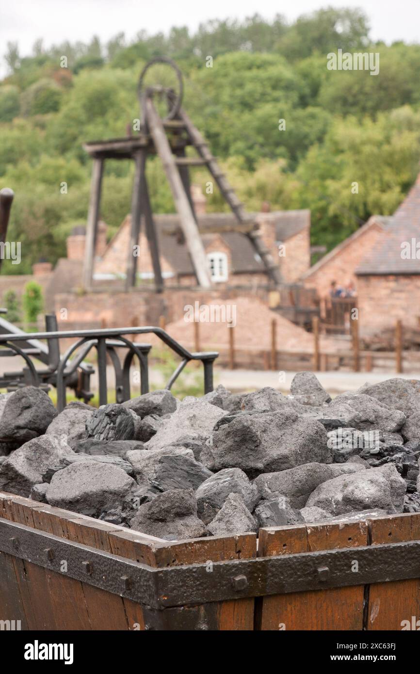 coal in a tub with old mining wheel in the background Stock Photo - Alamy