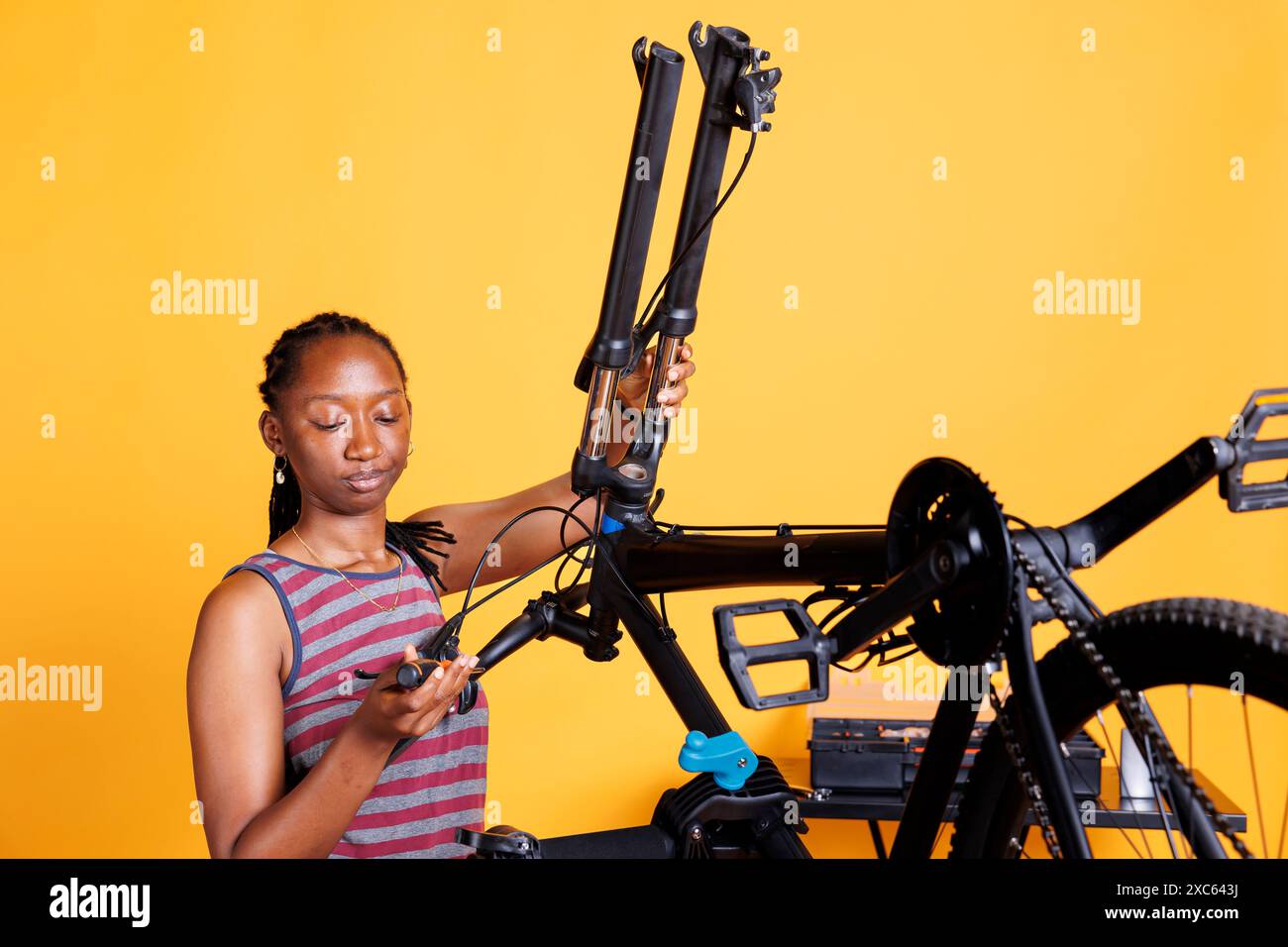 Youthful african american female cyclist immersed in fixing damaged ...