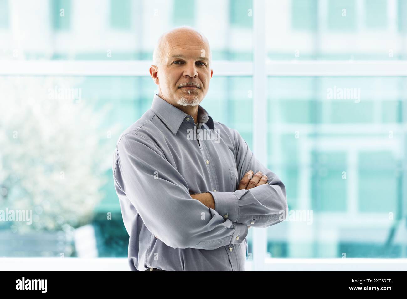 Confident mature businessman in office setting, arms crossed, exuding ...