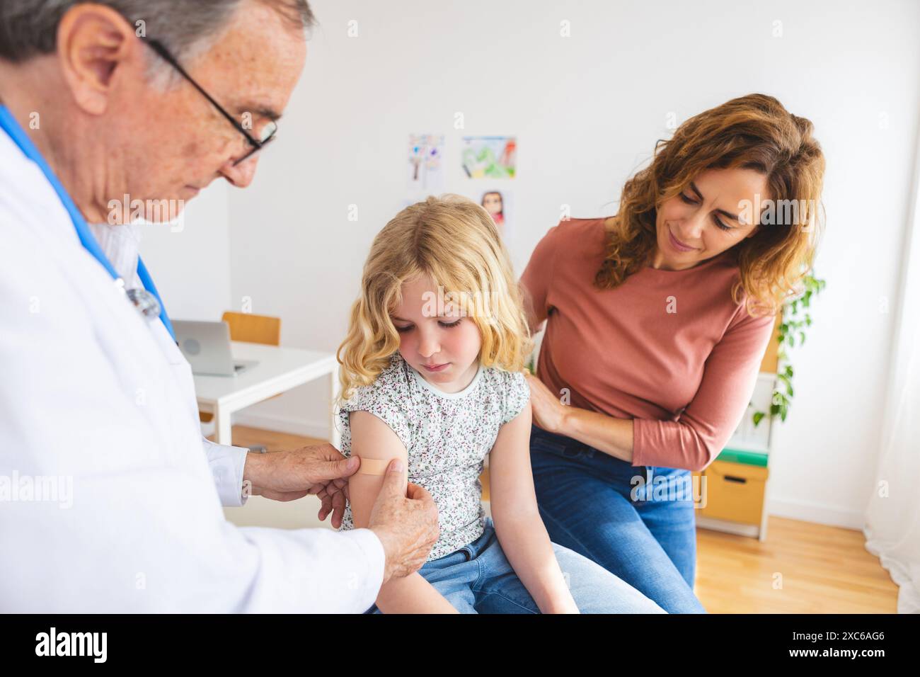 Senior pediatric doctor vaccinating child putting a bandage at hospital ...