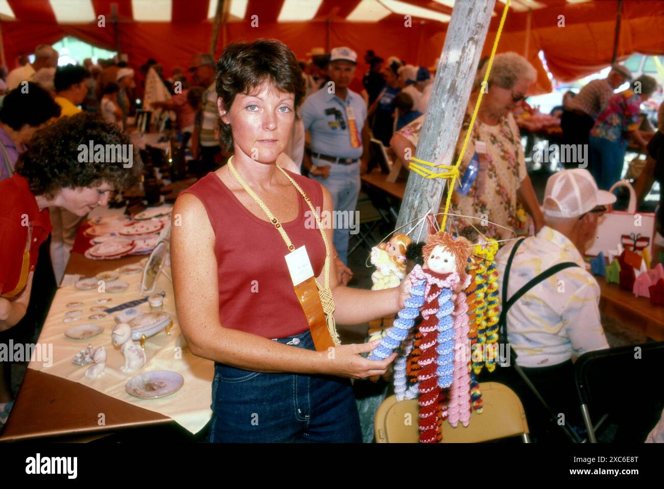 A participant shows off hand-made dolls at a craft fair as part of a ...