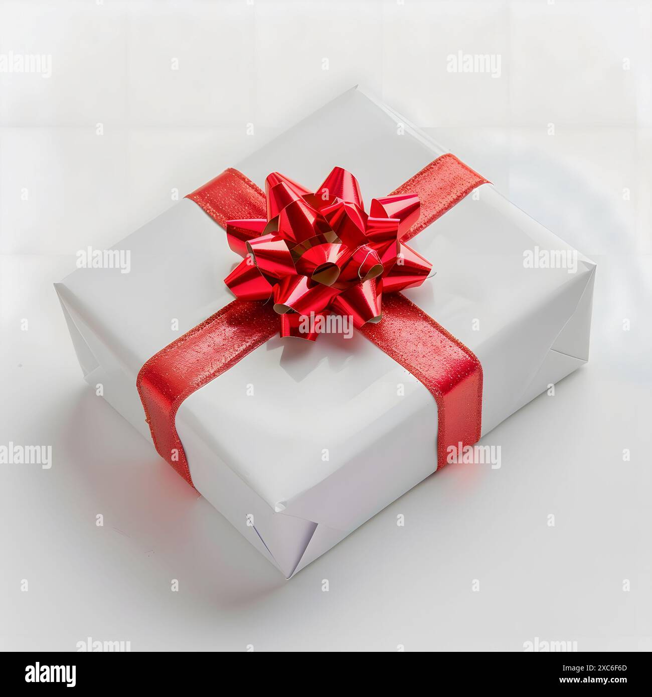 Present wrapped in white paper with red ribbon and bow on a white ...