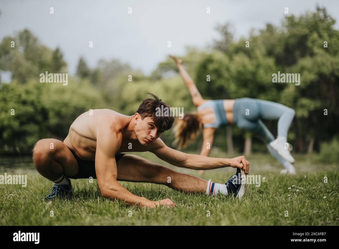 Young athletes stretching in a park, engaging in outdoor fitness and ...