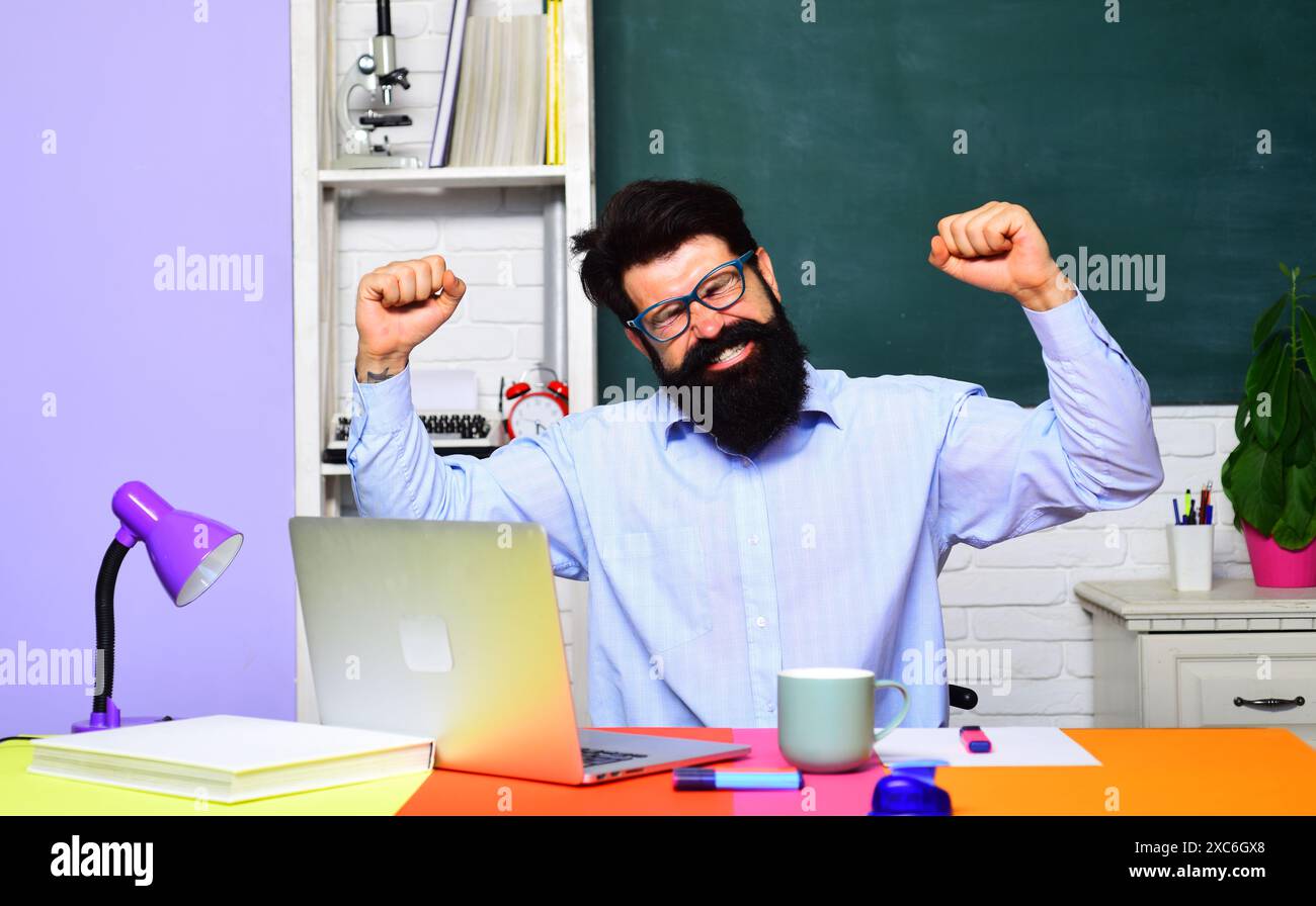 Bearded emotional professor in glasses working with laptop computer. E ...