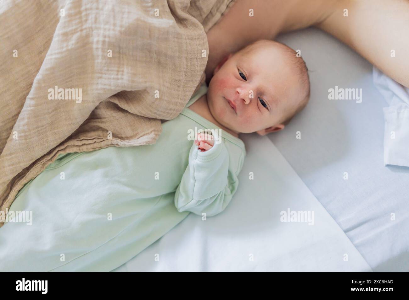 A baby lies with the mother after childbirth, resting peacefully. The ...