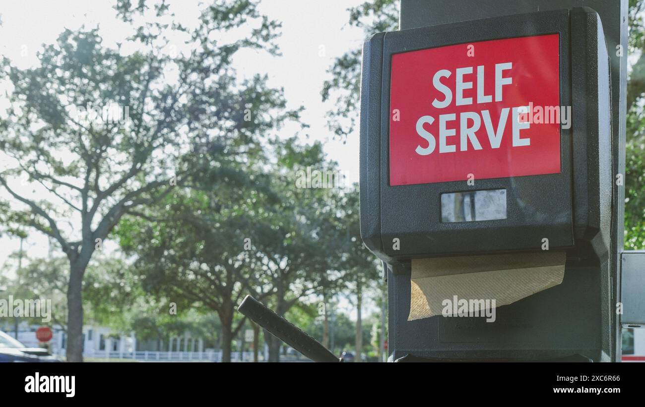 A tranquil self-serve gas station sign surrounded by lush green trees ...