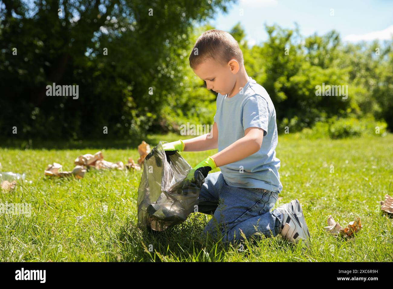 Little boy with plastic bag collecting garbage in park Stock Photo - Alamy