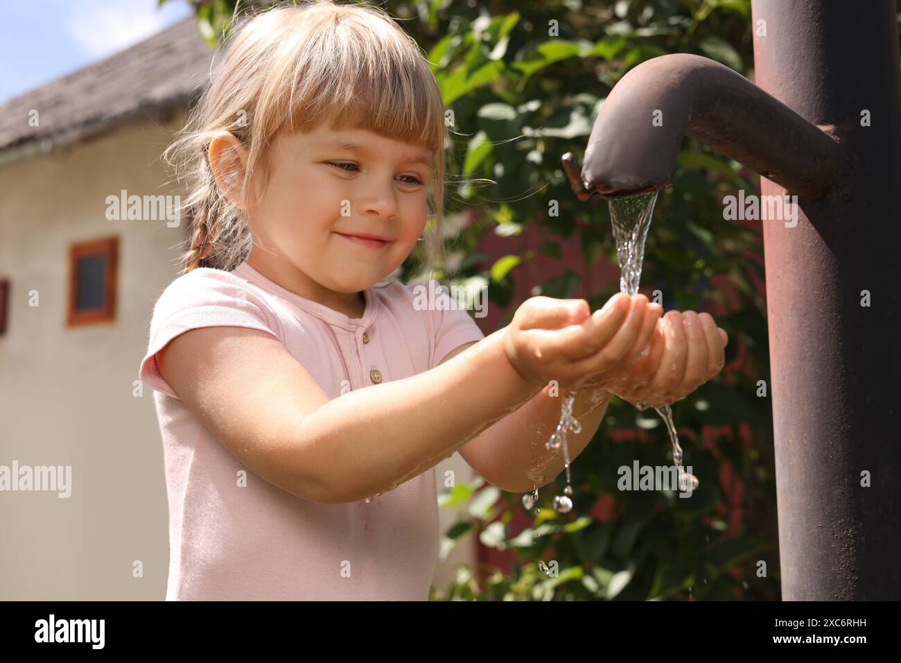 Water scarcity. Cute little girl drawing water with hands from tap ...