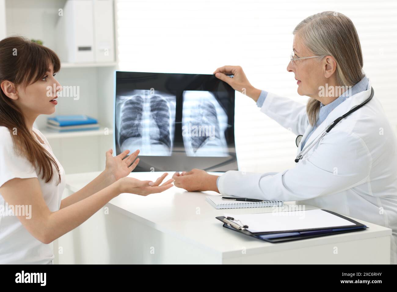 Lung disease. Doctor showing chest x-ray to her patient in clinic Stock ...
