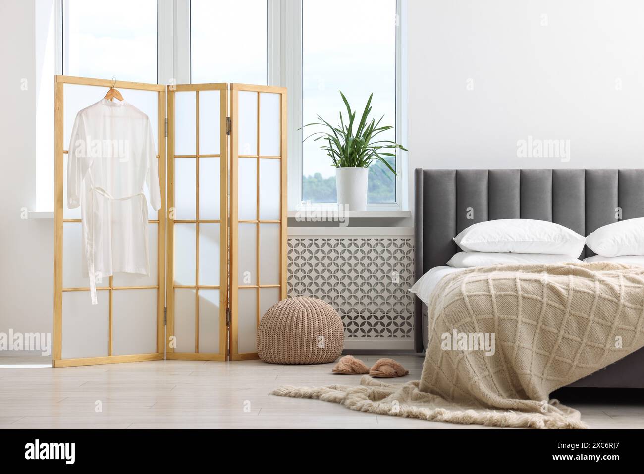 Folding screen, pouffe, bed and houseplant in bedroom Stock Photo - Alamy