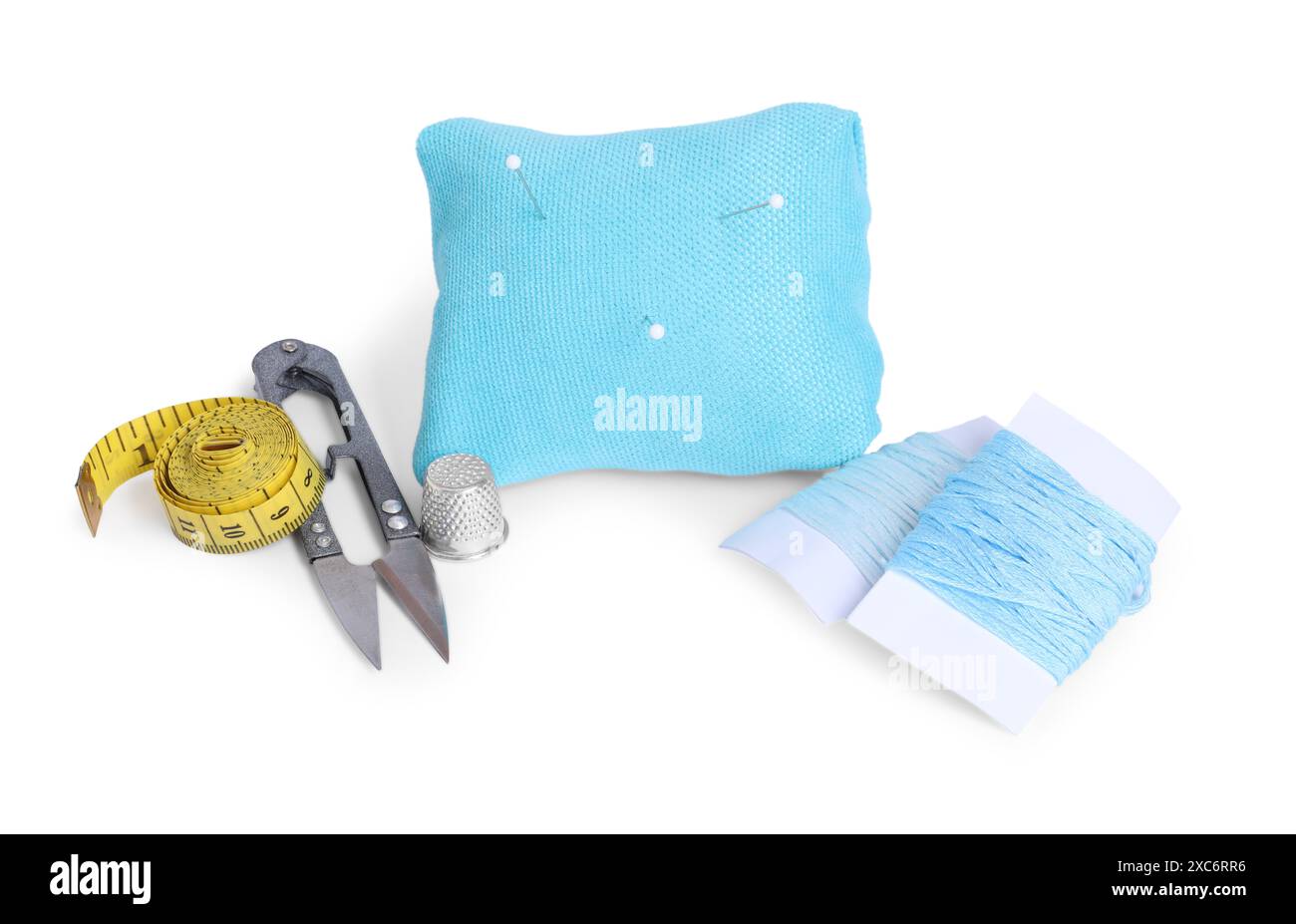 Light blue pincushion with sewing pins, cutter, threads, thimble and ...