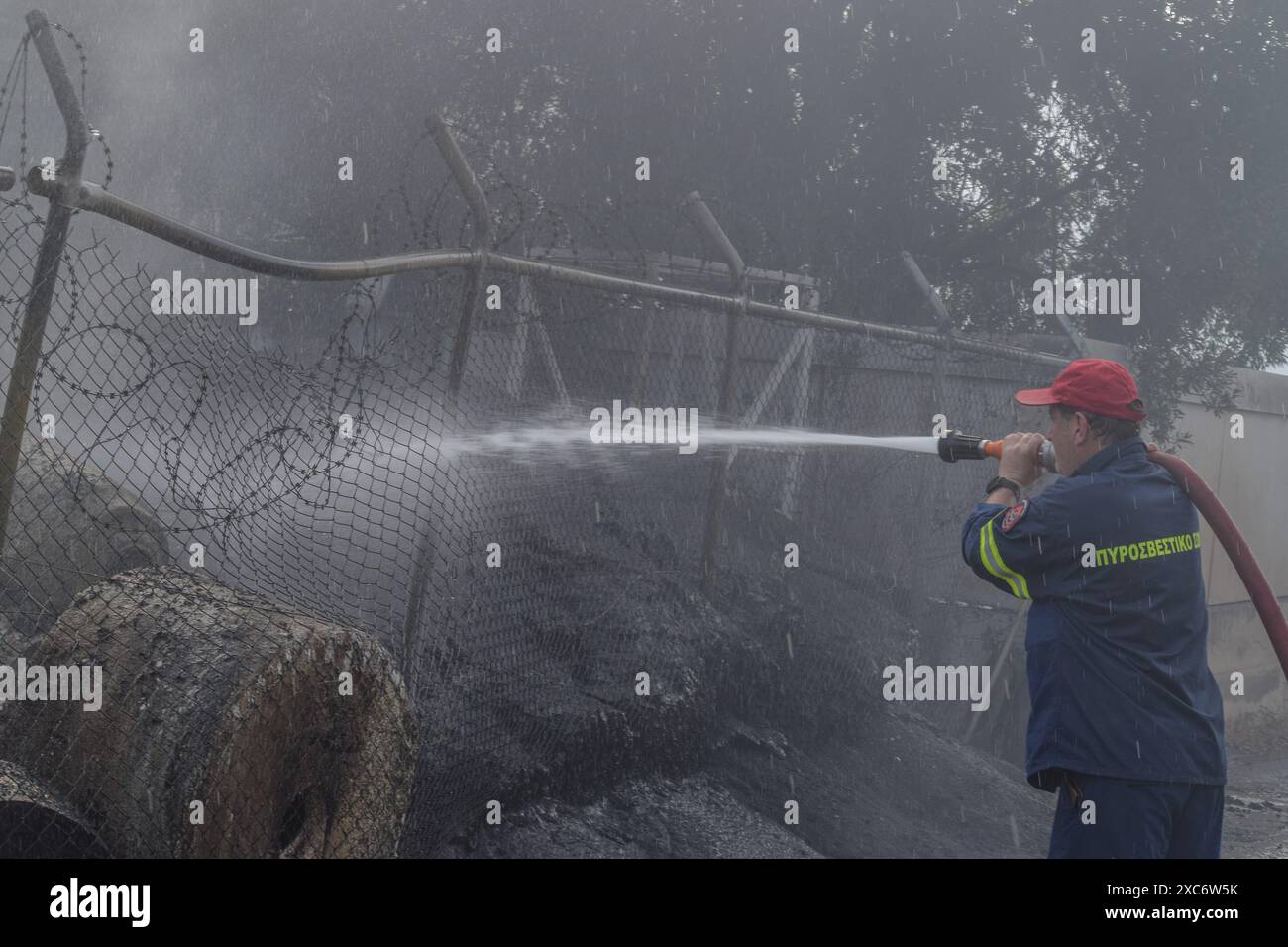Athens, Greece. 12th June, 2024. A firefighter operates amidst a smoke ...