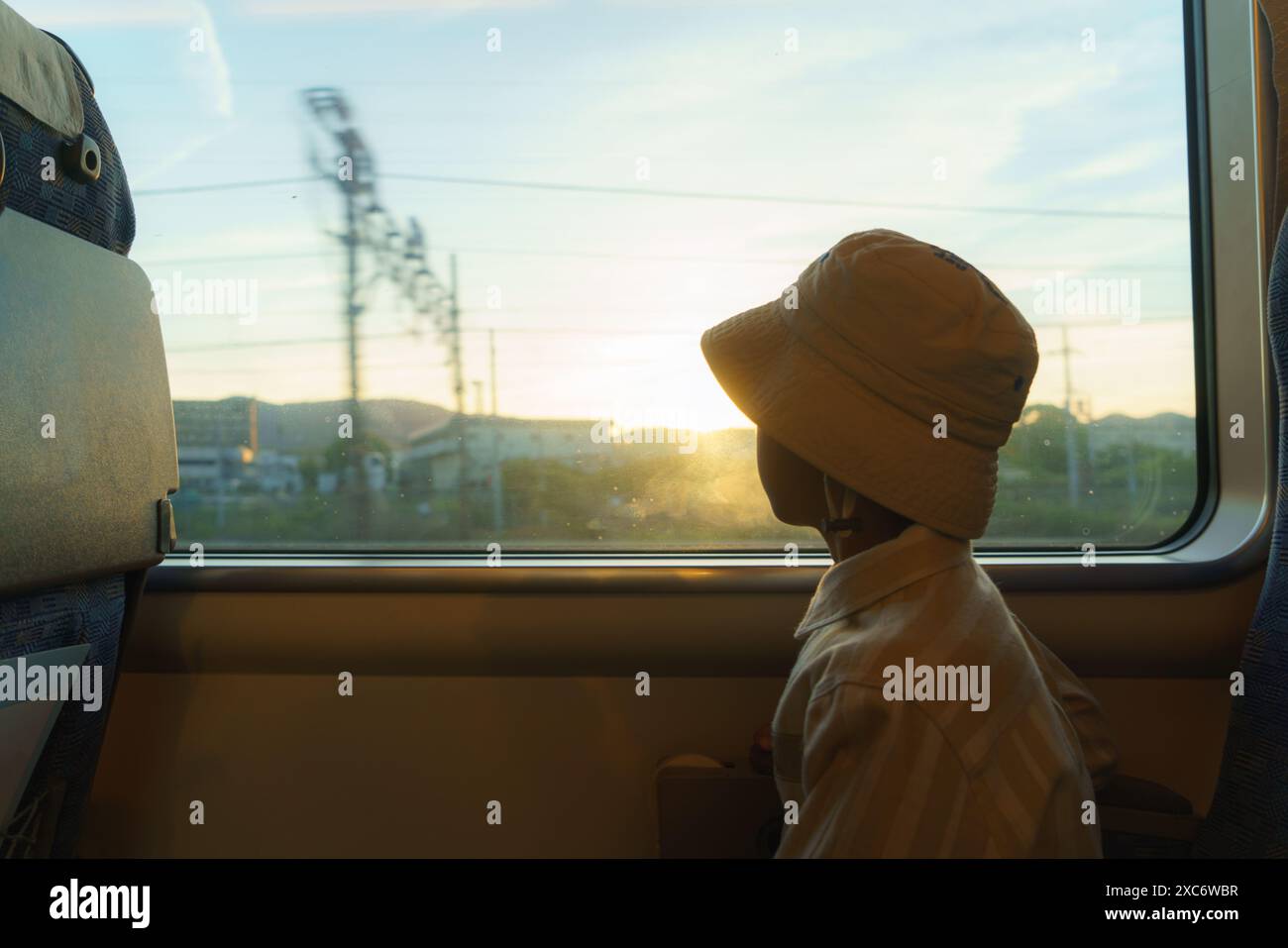 Asian young boy gazing out of a train window, captivated by the passing ...