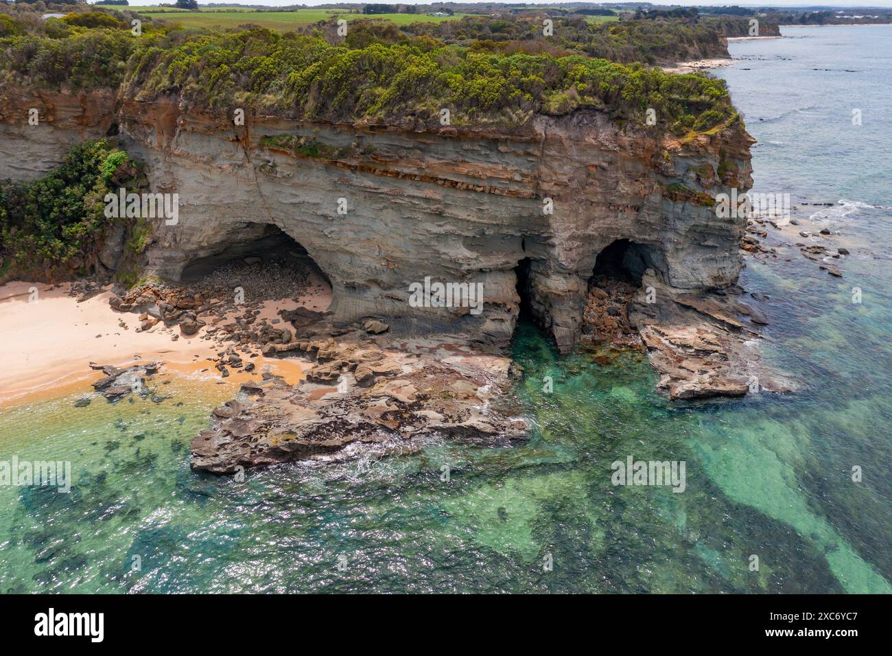 Aerial view of a rocky coastal headland with undercut caves at ...