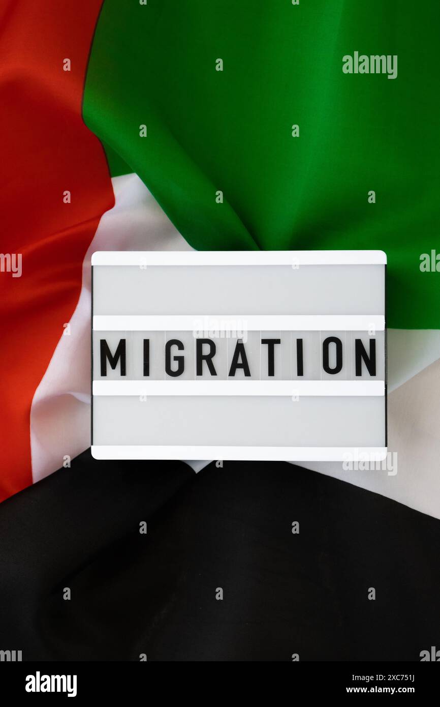 Message MIGRATION on background of UAE flag made from silk. United Arab ...