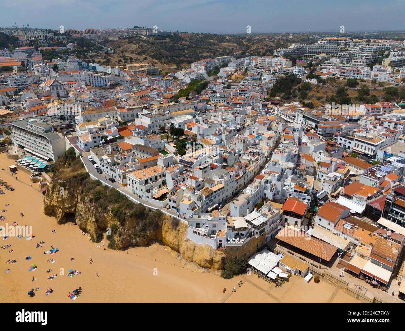 Coastal town with many white buildings on cliffs on the beach, sandy ...
