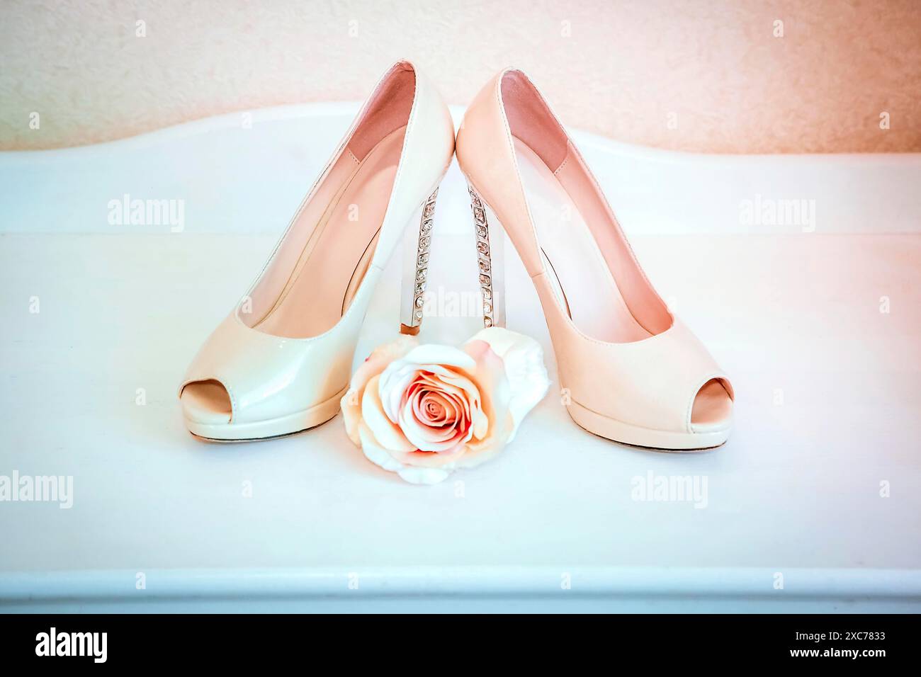 A pair of elegant white and beige high heels with a soft pink rose ...