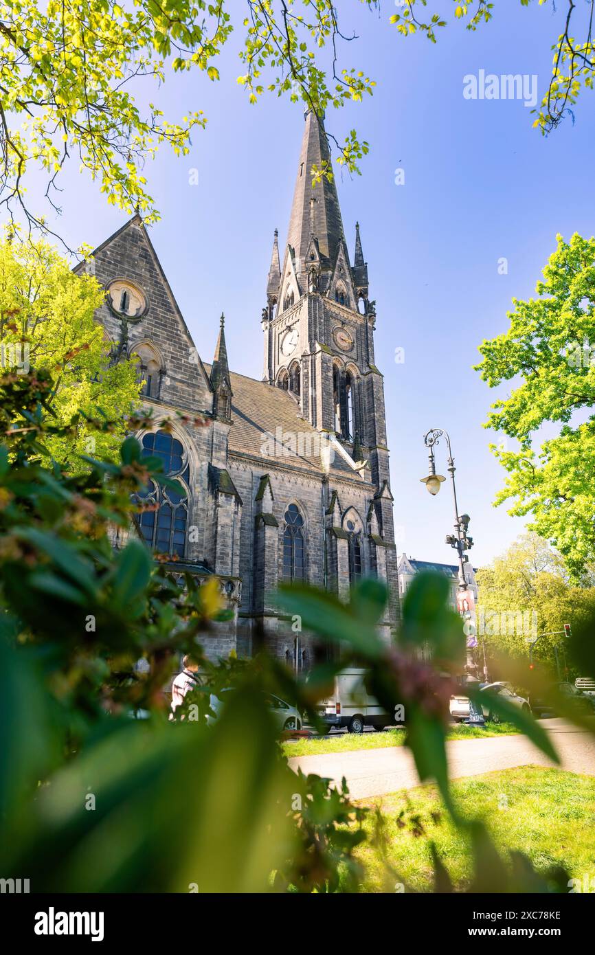 An impressive Gothic church with a high tower, surrounded by trees and ...