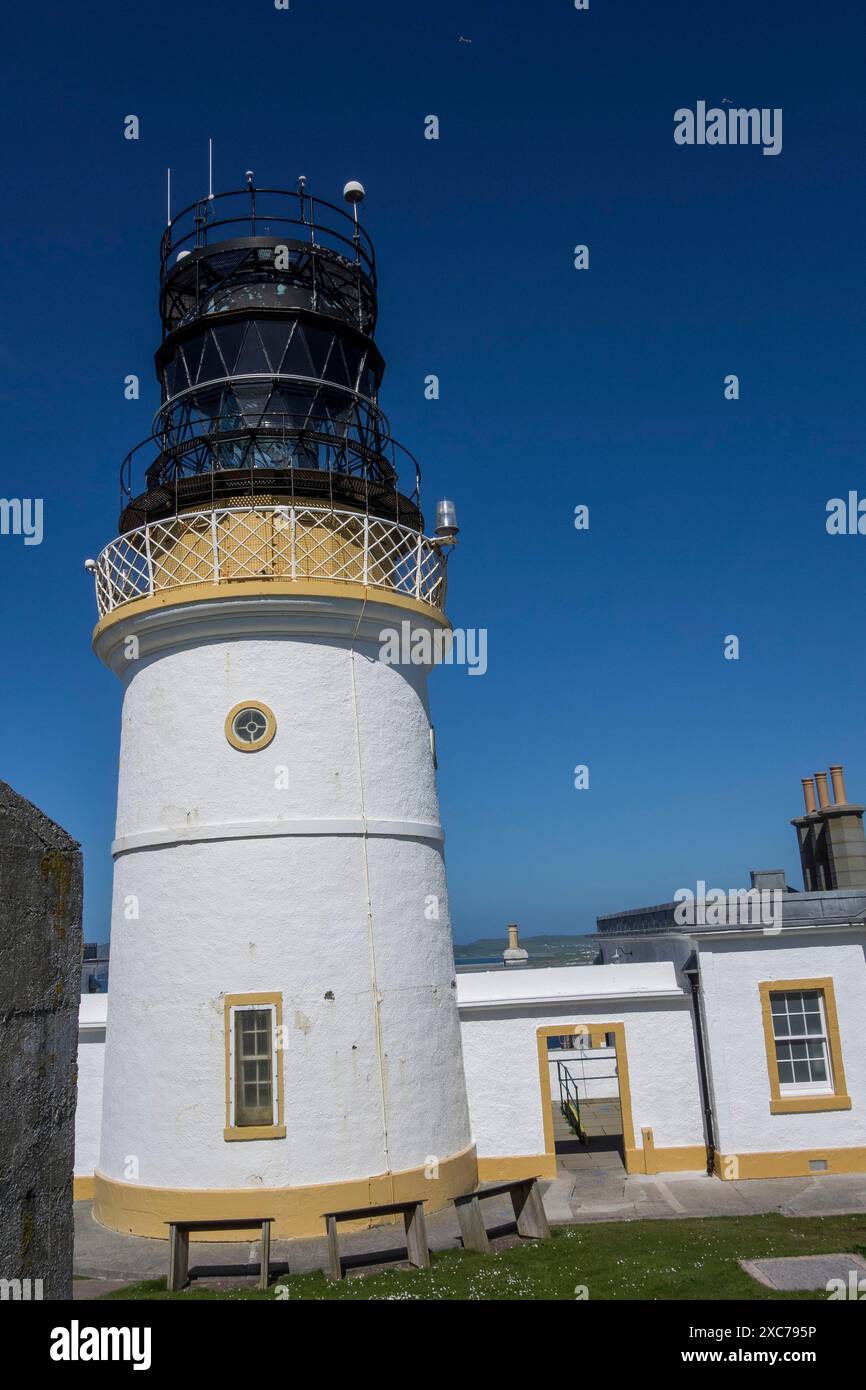 White and black lighthouse rises steeply into the clear blue sky ...
