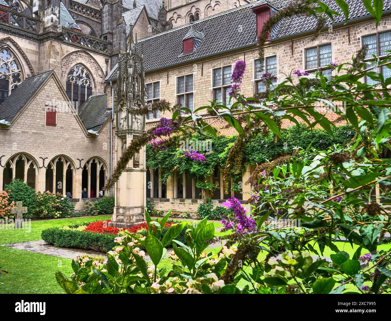 A peaceful garden with blooming flowers surrounded by Gothic buildings ...