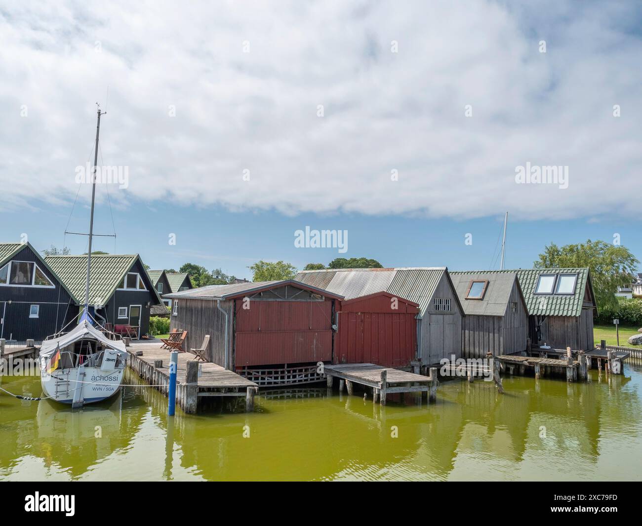 Wooden huts on stilts by the water with boats and jetty in typical ...