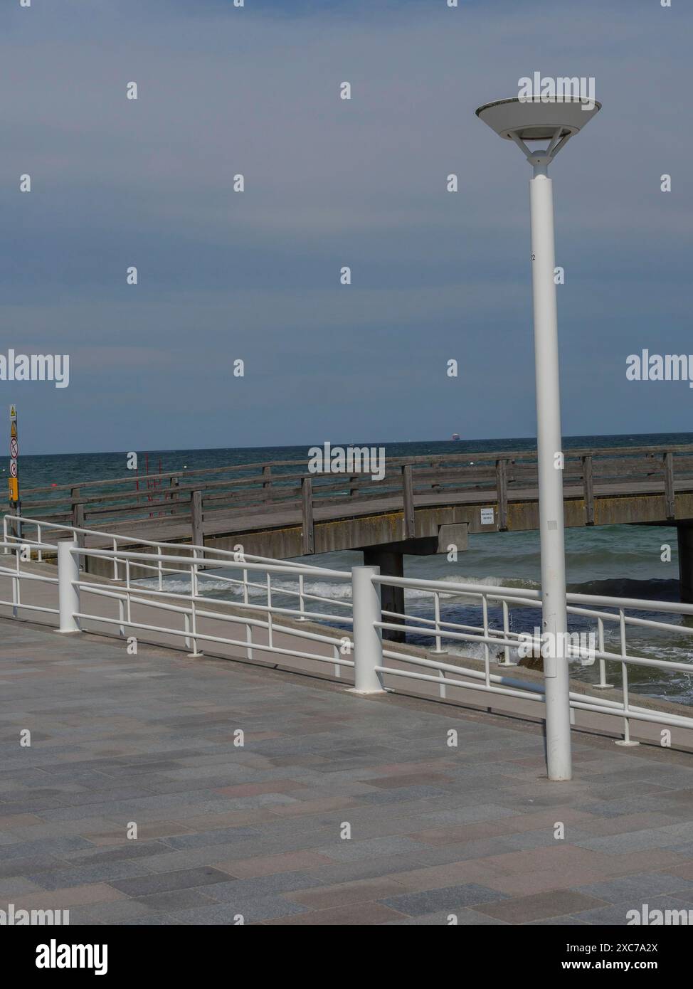 Empty promenade with a view of the sea, calming waves and a long wooden ...