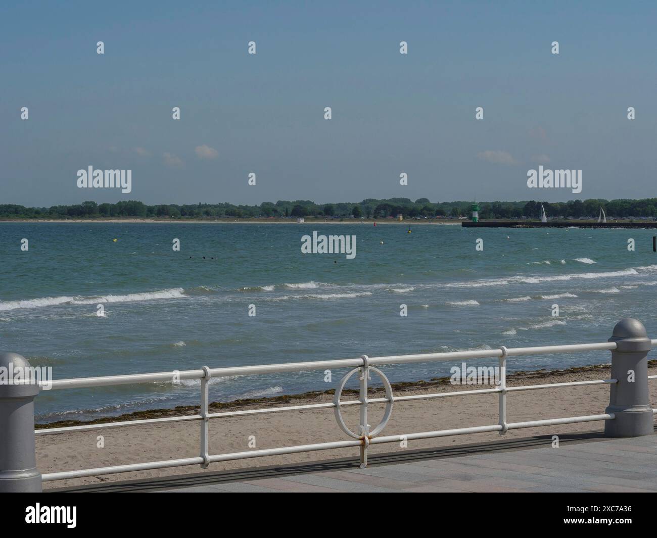 View of the sea and the waves from the beach, railing in the foreground ...