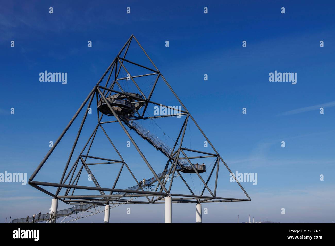 A modern steel pyramid with a central spiral staircase under a clear ...