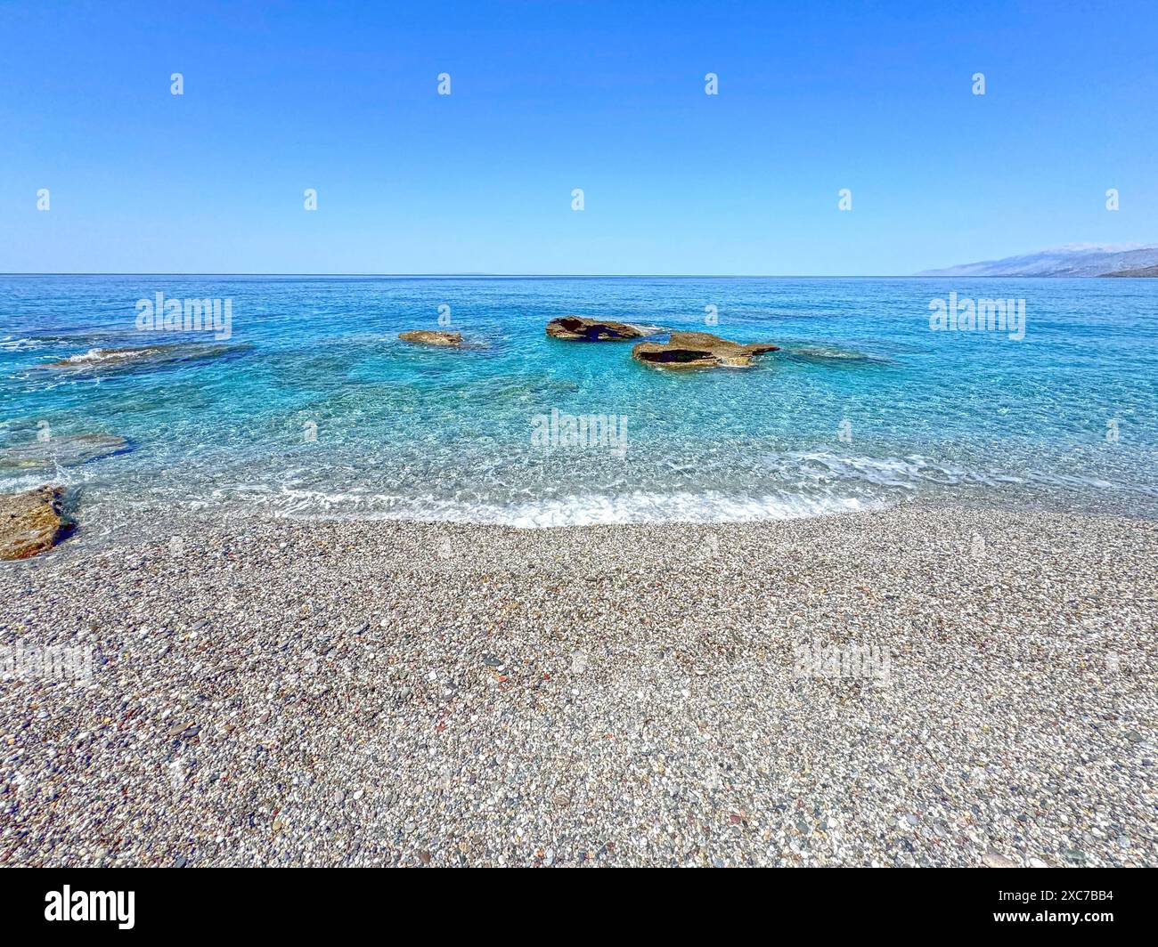 Fine pebble beach with small pebbles stones behind turquoise blue sea ...
