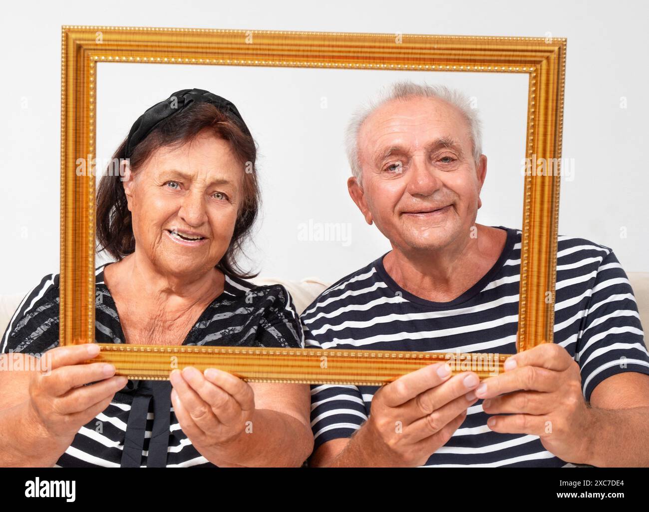 Senior couple portrait holding frame wall background Stock Photo - Alamy