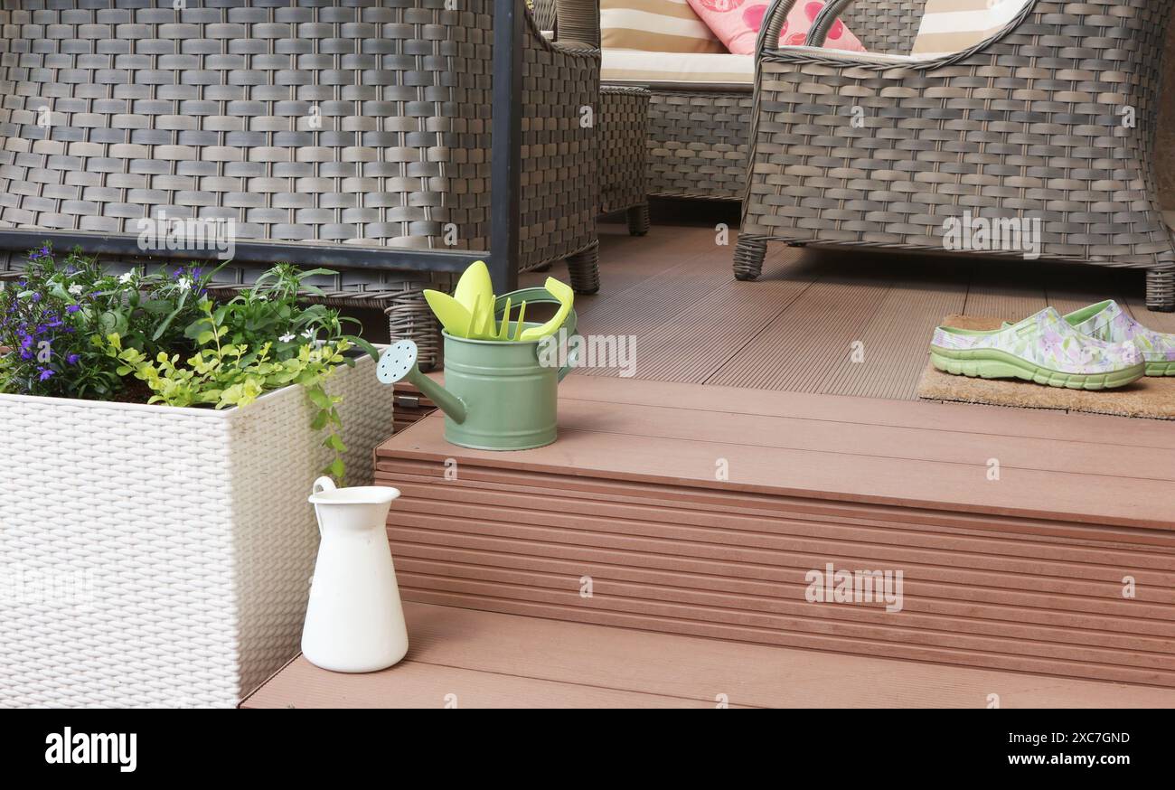 Sofa on terrace. Steps to patio. Backyard and flowers. Tools in garden ...