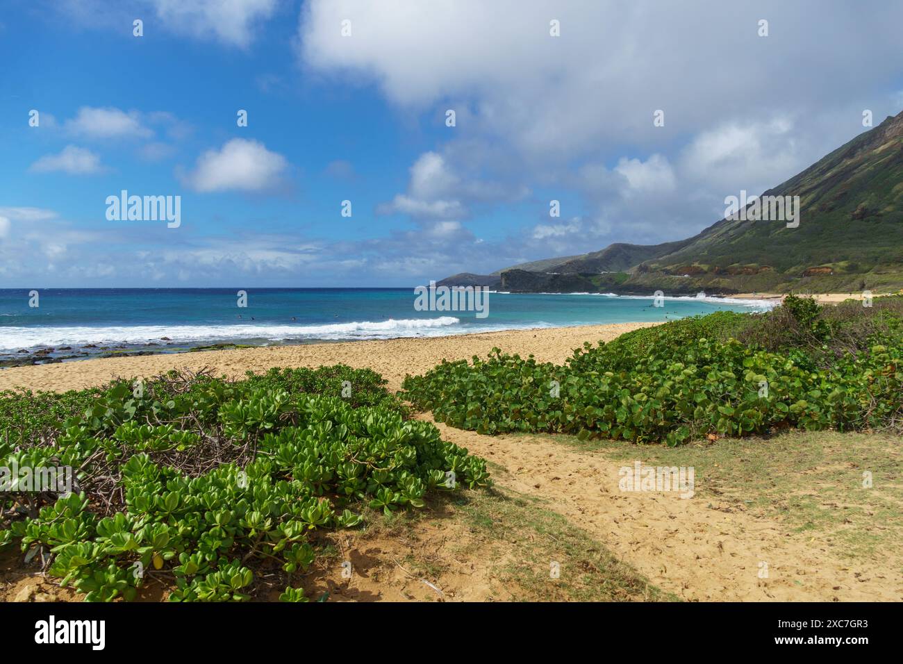 Scenic path to a sandy beach, overlooked by a mountain under a sky with ...